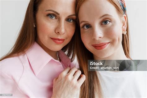 빨간 머리 엄마와 십대 소녀가 서로 가까이 서 있는 클로즈업 초상화 엄마는 몸짓 언어로 보호와 보살핌을 표현하고 아이의 어깨에 손을 얹고 있습니다 14 15 살에 대한 스톡