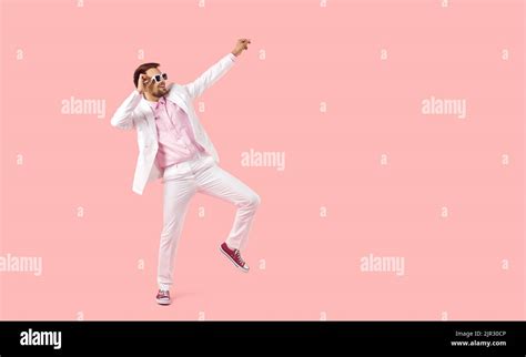 Happy Party Man In White Suit And Sunglasses Dancing Isolated On Pink