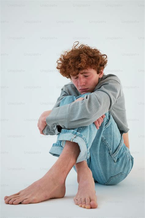 다리를 꼬고 땅에 앉아 있는 어린 소년 사진 Unsplash의 슬픔 이미지