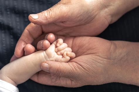 Free Photo The Handle Of A Newborn In The Hands Of A Grandmother Closeup