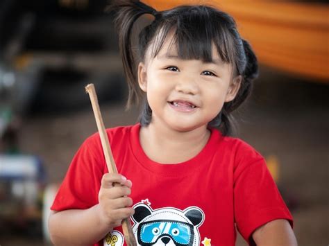 Premium Photo Portrait Of Cute Smiling Girl Holding Wooden Stick