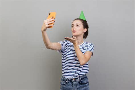 Woman In Party Cone Taking Selfie Sending Air Kisses To Followers Having Video Call Stock