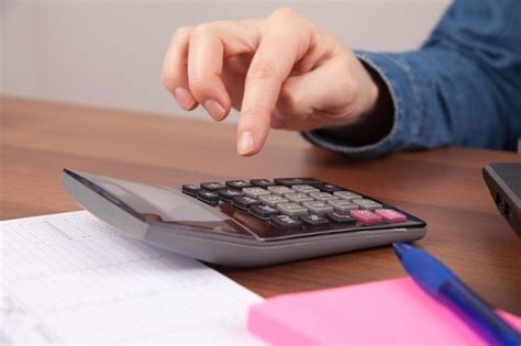 Premium Photo Cropped Hand Using Calculator Over Table