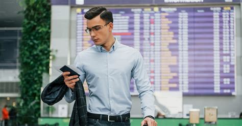 전화를 들고 정장을 입은 젊은 사업가가 낮에 공항에 있습니다 사진 Unsplash의 공항 이미지