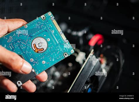A Person Holding A Blue Circuit Board Of A Hard Disk Drive With A Computer In The Background