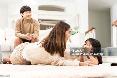 행복한 아시아 가족 바닥에 누워있는 작고 귀여운 딸과 아내를 보며 미소 짓는 아버지 등교 첫날 등교 준비를 위해 책을 읽고
