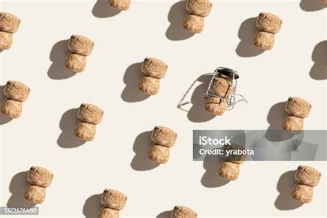 베이지 색 배경에 샴페인 코르크패턴이 있고 햇빛에 딱딱한 빛과 그림자가 있습니다 스파클링 와인과 메탈 와이어 뮤슬렛의 병 캡이 있는 트렌드 레이아웃 반복 패턴 탑 뷰 0명에