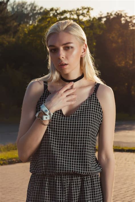 Pretty Tanned Blonde Woman In Black Romper Posing At The City In Stock