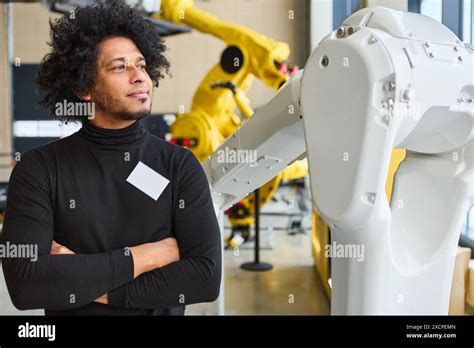 Engineer Attentively Observing A Robotic Arm In A Contemporary Industrial Environment Focusing