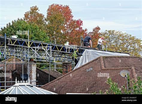 Scaffolders Erecting Scaffold On A Suburban Bungalow Prior To Building