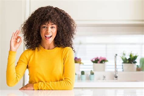 아프리카계 미국인 여자는 부엌 손과 손가락으로 Ok 사인을 하 고 긍정적인 미소에 노란색 스웨터를 입고 성공적인 식입니다 곱슬 머리에 대한 스톡 사진 및 기타 이미지