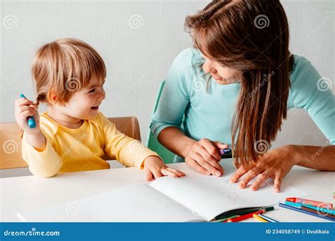 La Mamma Insegna Alla Sua Bambina A Disegnare Madre E Figlia Sono Sedute A Un Tavolo E
