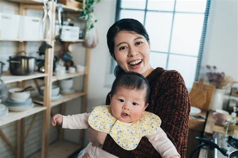 Premium Photo Dutch Angle Shot Joyful Asian First Time Mom Holding A Lovely Baby Is Smiling At