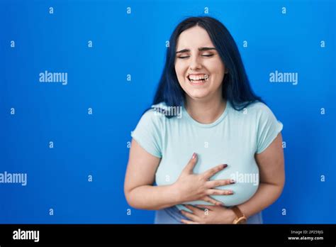 Young Modern Girl With Blue Hair Standing Over Blue Background Smiling