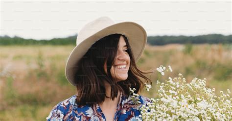 시골의 여름 파란색 빈티지 드레스와 모자를 쓴 세련된 젊은 여성이 여름 초원에서 흰색 야생화와 함께 걷고 있다 들판에서 데이지 꽃다발과 함께 웃고 있는 행복한 아름다운