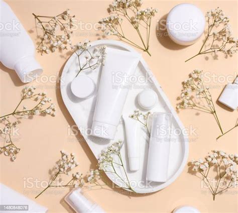 베이지색 배경에 흰색 플라스틱 튜브 항아리 및 Gypsophila 가지 화장품 크림 및 젤용 용기 광고 및 브랜드 프로모션 상위