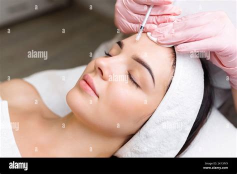 Close Up Of Hands Of Young Cosmetologist Injecting Botox In Female Face