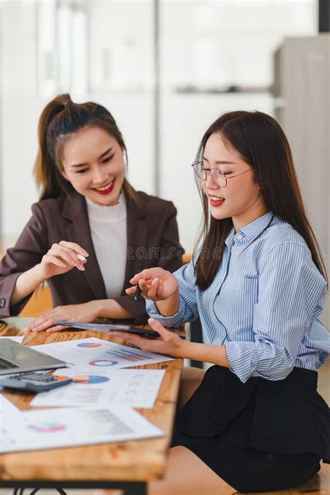 Two Colleagues Engaged In Business Analytics Using Digital Tablets Over Financial Charts