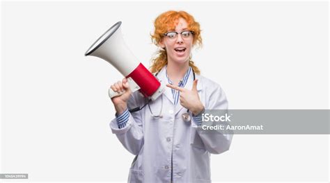 손과 손가락으로 가리키는 매우 행복 확성기를 들고 빨간 머리 젊은 의사 여자 가리키기에 대한 스톡 사진 및 기타 이미지 가리키기 감정 건강관리와 의술 Istock