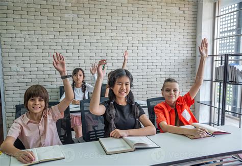 Elementary School Students Raise Their Hands To Ask Class Teacher