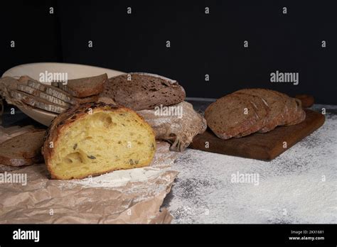 Different Types Of Sliced Bread And A Loaf On A Wooden Background Spilled Flour Front View