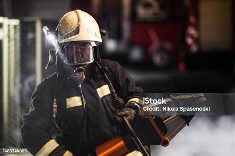 전체 장비와 산소 마스크를 착용한 소방관 초상화 동력 유압 절삭 공구를 갖춘 소방관 배경에 연기와 소방차가 있습니다 소방관에 대한 스톡 사진 및 기타 이미지 Istock