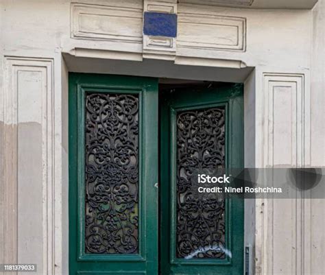 녹색 은근한 직사각형 프레임에 빈티지 화려한 금속 격자 와 녹색 페인트 나무 이중 문 프랑스에서 오래 된 치장 벽토 건물의 파리 문 건축 세부 사항입니다 골동품 질감
