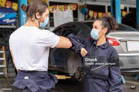 건강을 위해 얼굴 마스크를 쓰고 있는 전문 남녀 정비사 직원이 자동차 수리점에서 코로나바이러스 또는 Pm 25 인사말 부딪치는 팔꿈치를 보호합니다 자동차 수리 서비스 및