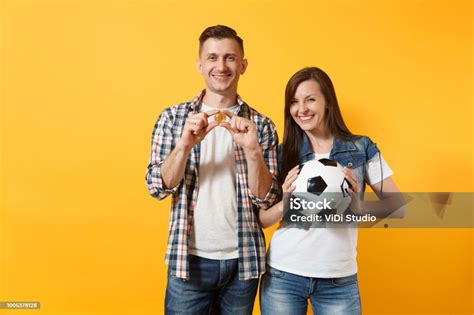 젊은 커플 여자 남자 팬 들고 Bitcoin 금속 황금 동전 축구공 노란색 배경에 고립 된 지원 팀을 응원 하는 축구 승리