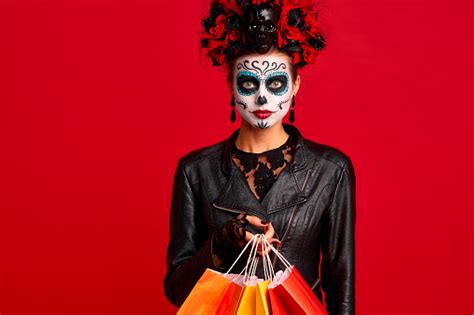 그녀의 머리와 두개골에 꽃화환과 설탕 두개골 메이크업 소녀 착용 레이스 장갑과 가죽 재킷 빨간 배경에 고립 된 구매자 가방 파티 준비를 개최 11월에 대한 스톡 사진 및