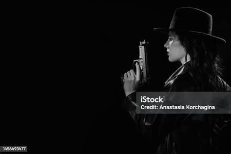 코트와 모자를 쓰고 손에 총을 든 여성 형사의 실루엣 1950 년대 탐정 스타일의 책 드라마 누아르 초상화 범죄에 대한 스톡