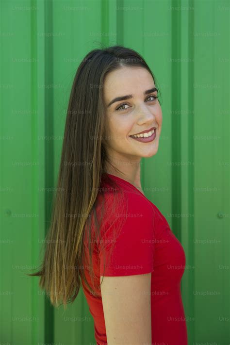 Trendy Young Woman Standing By The Green Wall On A Hot Summer Day Photo