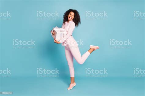 우리의 생일 소년은 어디 입니까 큰 포장 된 기프트 박스를 들고 놀라운 물결 모양의 어두운 피부 아가씨의 전체 길이 프로필 사진은 파티 착용 핑크 셔츠 바지 고립 된 파란색