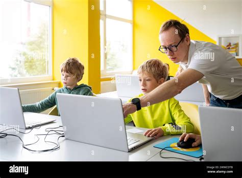 Professor Teaching Computer Coding To Boy With Laptop In Classroom Stock Photo Alamy