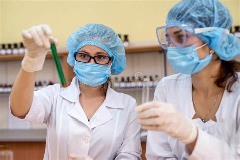 Chemical Experiment Two Women In Protective Uniform With Test Tubes In Laboratory Stock Photo