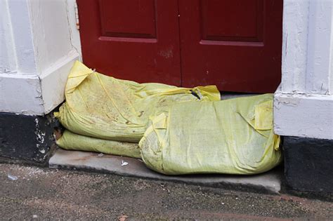 홍수로 인해 물이 부동산에 들어가 물 피해를 입힐 위험이 있기 때문에 Shrewsbury England의 상점 문 길에 쌓인 샌드백 모래 주머니에 대한 스톡 사진 및 기타