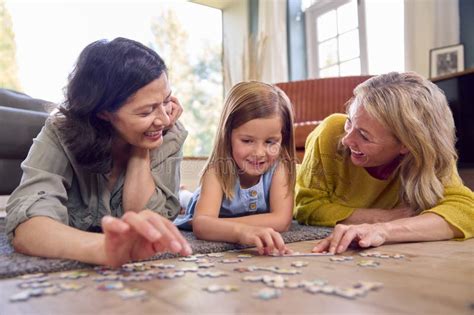 Familia Del Mismo Sexo Con Dos Madres Maduras E Hija Tumbadas En El Piso Haciendo Rompecabezas
