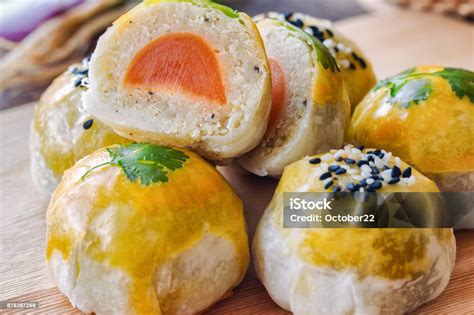 중국 생 과자 또는 달 케이크 녹두 반죽으로 가득 하 고 소금에 절인 계란 노 른 자 참 깨와 고 수 보기 매크로 스타일 가까이에 나무 절단 보드에 장식 수 제 베이커리