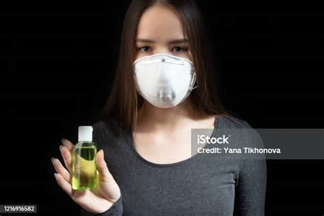 방부제 젤 바이러스 및 질병의 확산에 대한 예방 및 보호 흰색 항균 의료 마스크에 젊은 여성은 검은 배경에 병을 보유하고