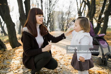 행복한 엄마와 아이 소녀의 초상화를 닫고 화창한 날에 아름다운 가을 공원에서 재미있게 놀고 웃고 Litlle 소녀가 비누 거품을 불고 있습니다 2명에 대한 스톡 사진 및