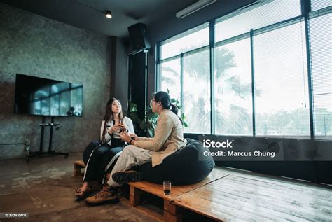 Two Asian Chinese Young Adult Sitting On Sofa And Having Lunch At Office Resting Area Stock