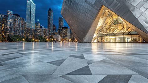 A Modern Architectural Structure With A Geometric Design Against A City Skyline At Dusk Stock
