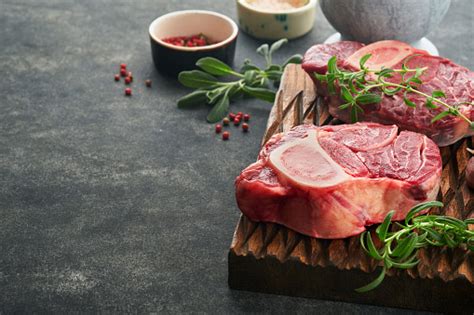 오소 부코 생 스테이크 고기 바베큐 고기 원시 신선한 크로스 컷 송아지 정강이와 조미료 후추 로즈마리 백리향 및 오래된 나무 소박한 배경에 소금 골수로 쇠고기 다리 슬라이스