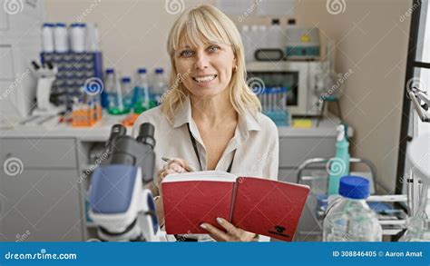 Blonde Woman Scientist In Lab Coat Reading A Notebook Within A Modern