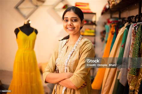 젊은 인도의 행복한 여성 재단사 재봉사 패션 디자이너 웃고 의류 작업장 아틀리에 또는 스튜디오에서 팔짱을 끼고 측정 테이프를