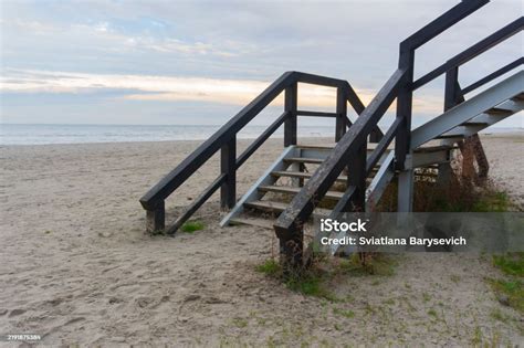 계단이 있는 해변의 목가적인 풍경 고운 모래와 끝없는 수평선의 전망이 있는 넓은 해변 갈색 계단은 모래와 물의 자연스러운 그늘과 대조를 이룹니다 0명에 대한 스톡 사진 및