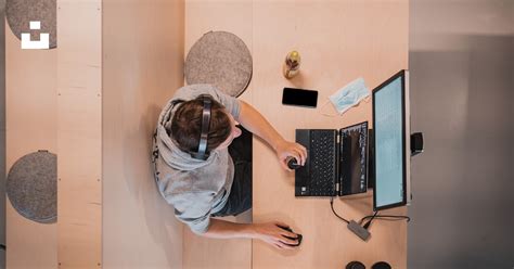 파란 셔츠를 입은 여자가 노트북 컴퓨터를 사용하여 의자에 앉아 있다 사진 Unsplash의 무료 책상 이미지