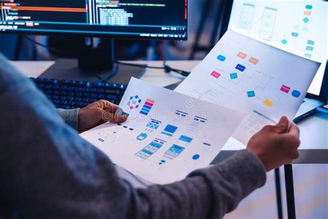 Software Developer Reviews Ux Ui Design Diagrams While Coding At A Workstation Stock Image