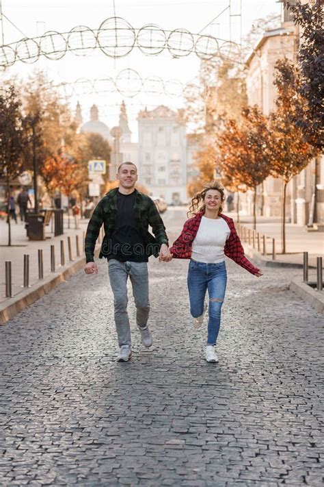 Joyful Couple Running Hand In Hand Through A Scenic Urban Street Stock Image Image Of Cute