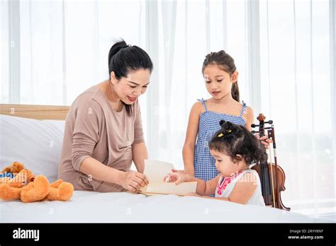Asian Mother Teaching Mixed Raced Girls Daughter To Reading Books In Their House Quarantine In